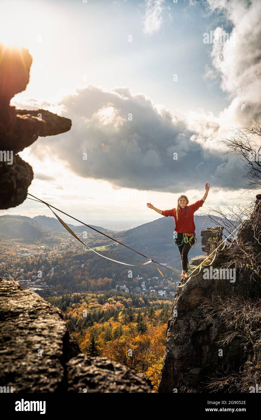 Woman with arms raised slacklining amidst mountains at Baden-Baden ...