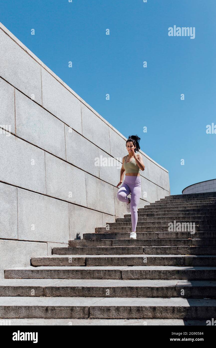 Female athlete running on steps during sunny day Stock Photo - Alamy