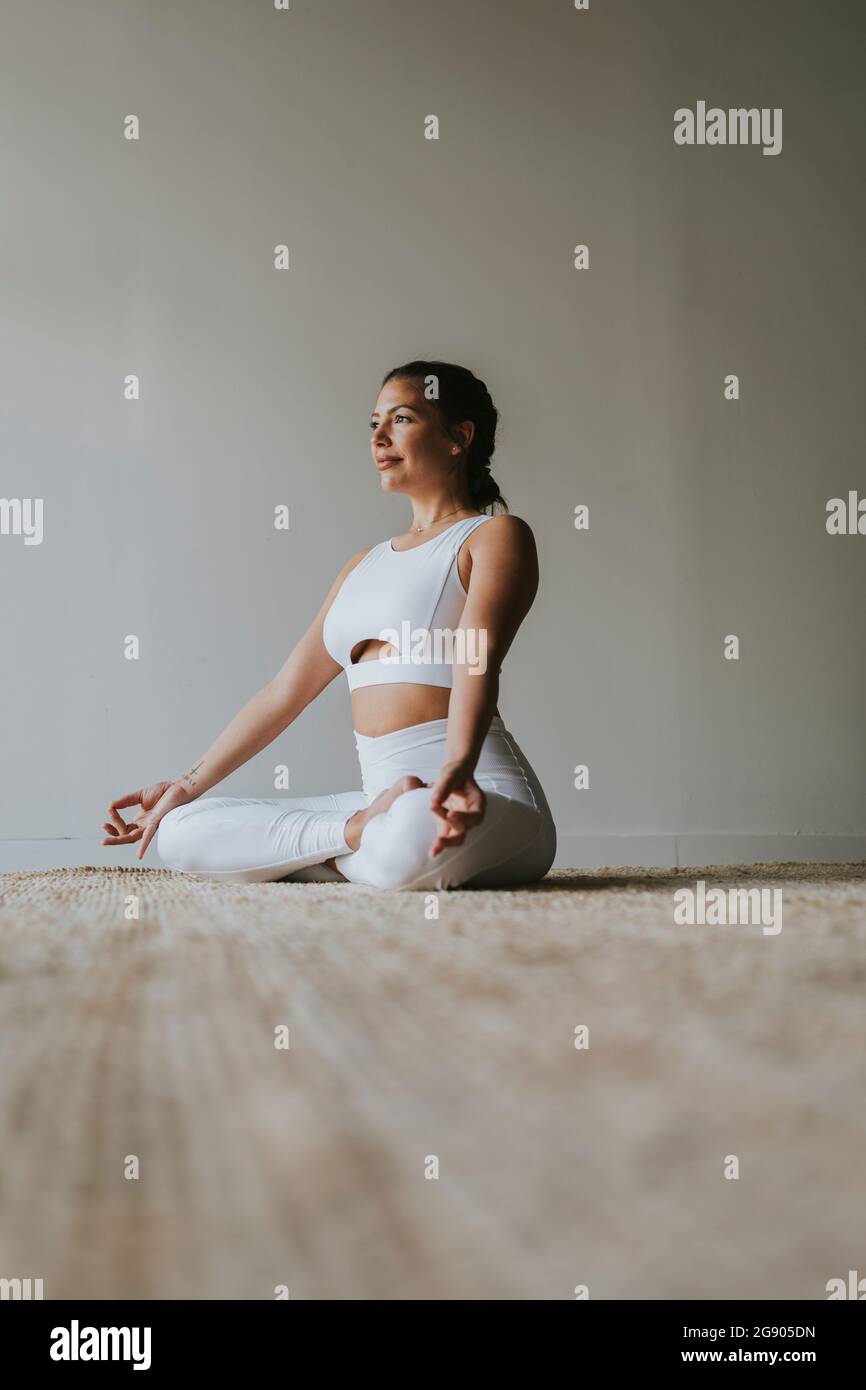 Yogi meditating while sitting cross-legged on carpet at health club ...