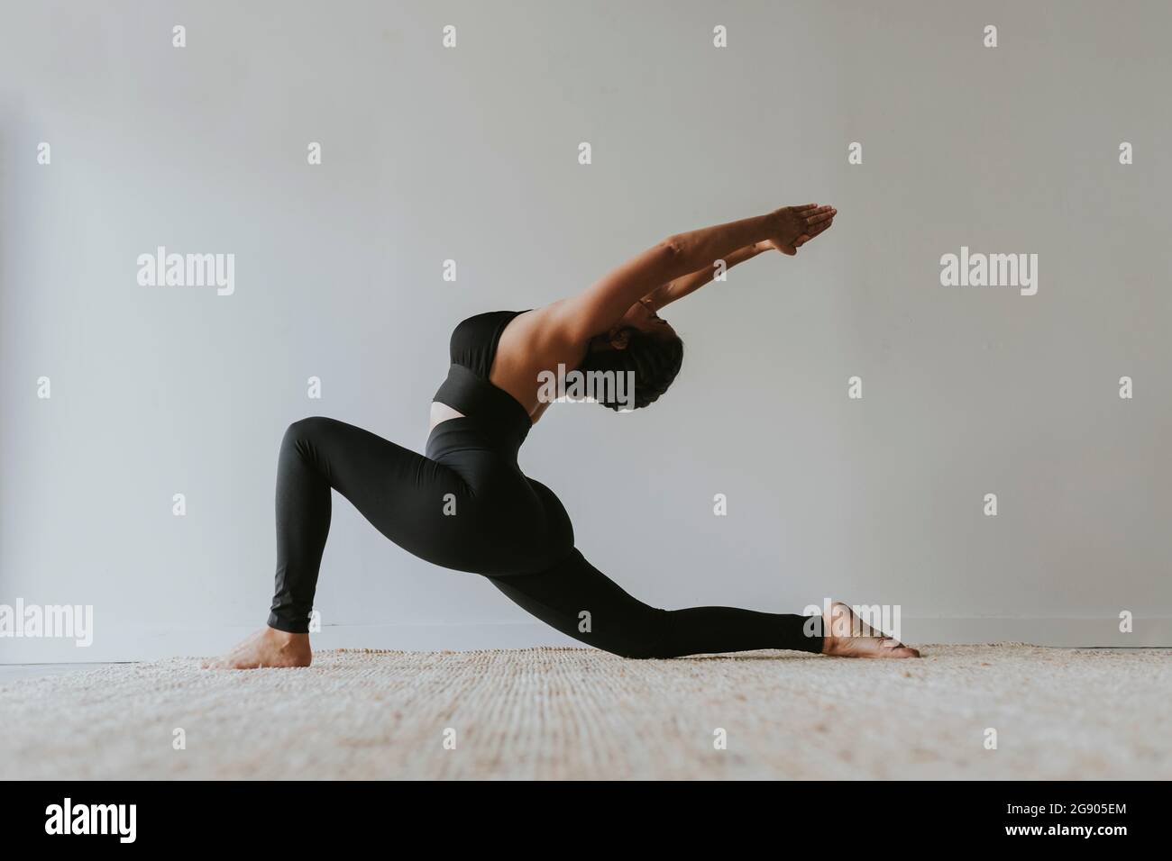 Female fitness teacher with arms raised bending backwards while ...