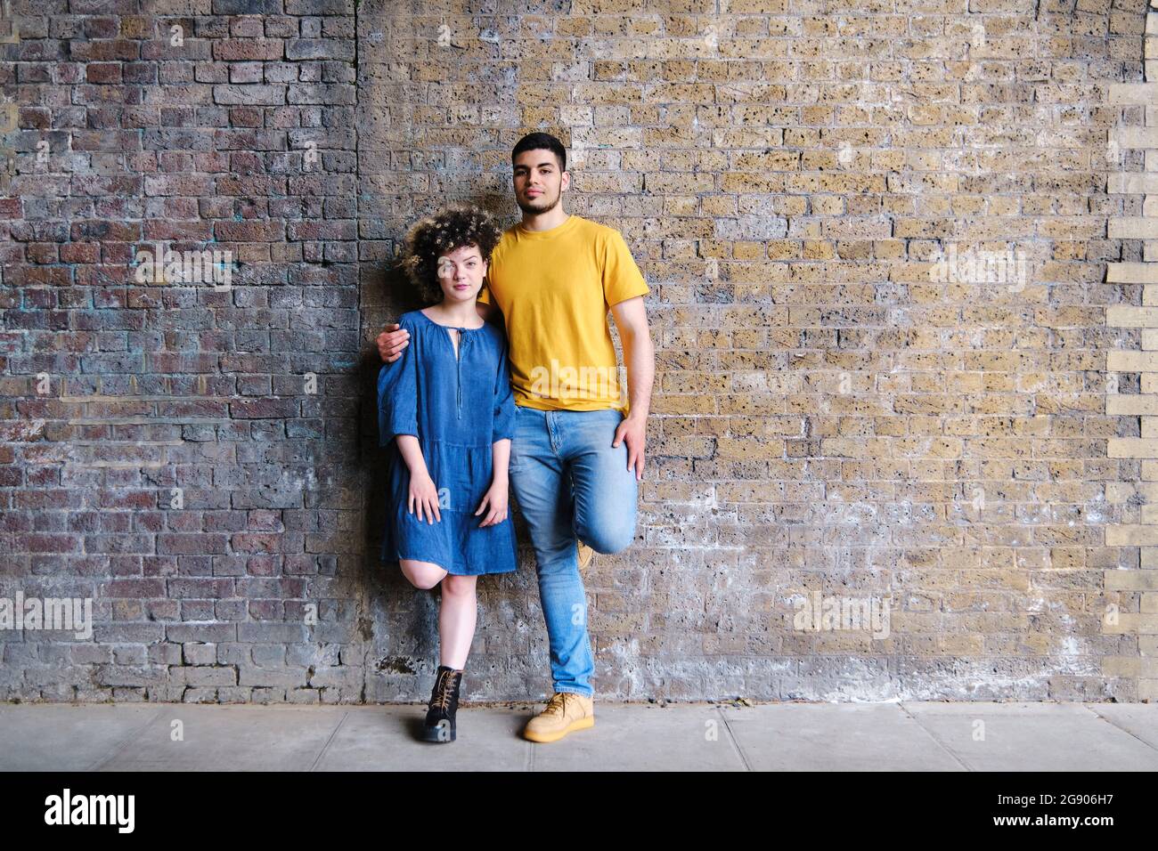 Young couple standing together on one leg in front of wall Stock Photo ...