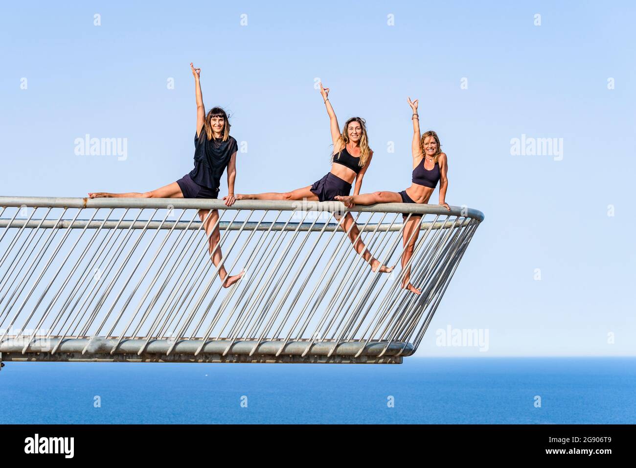 Mature women practicing acrobatic activity on railing at observation ...
