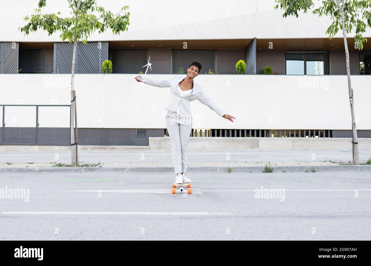 Businesswoman with arms outstretched holding wind turbine model while ...