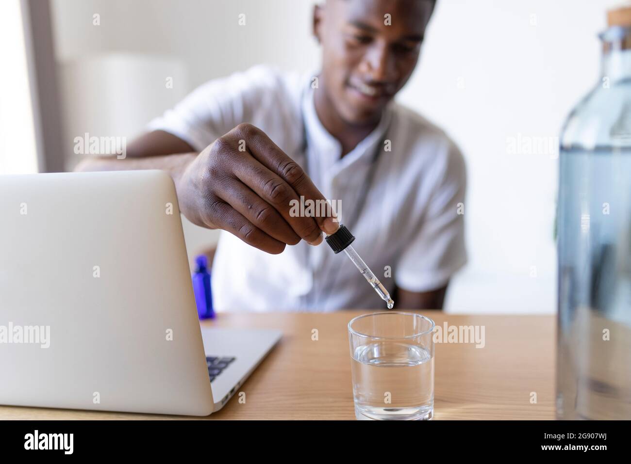 Man mixing medicine in water through dropper at home Stock Photo - Alamy