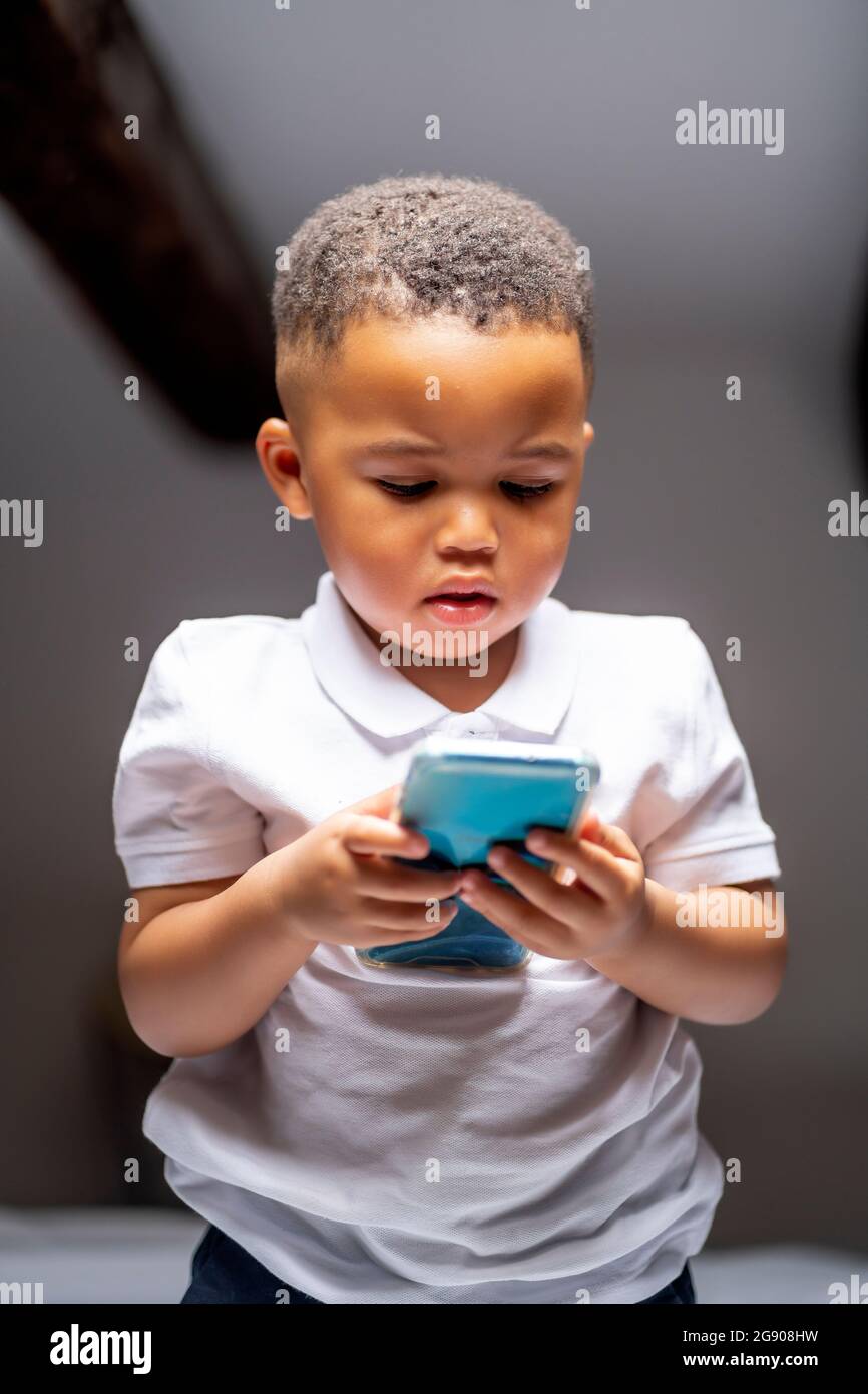 Cute boy using smart phone at home Stock Photo - Alamy