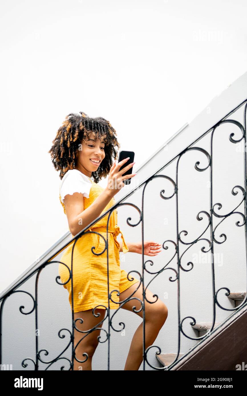 Woman using smart phone while walking on staircase Stock Photo - Alamy