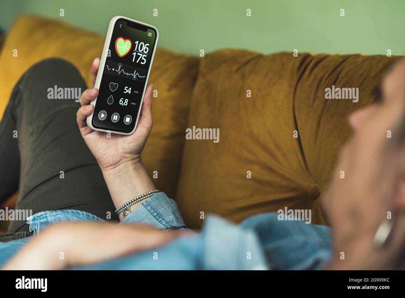 Woman examining pulse trace record through smart phone at home Stock ...