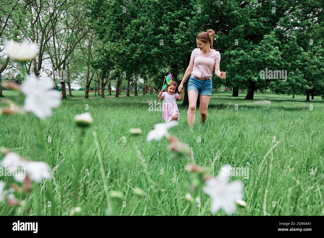 Girl holding pinwheel while walking with mother at park Stock Photo - Alamy
