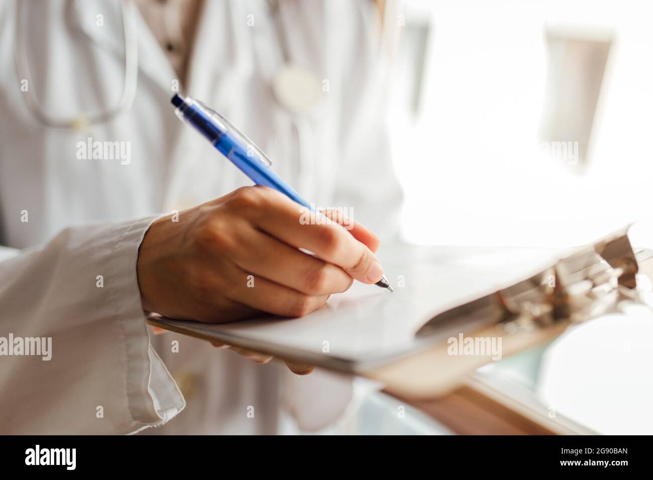 Female doctor writing medical record on clipboard Stock Photo - Alamy