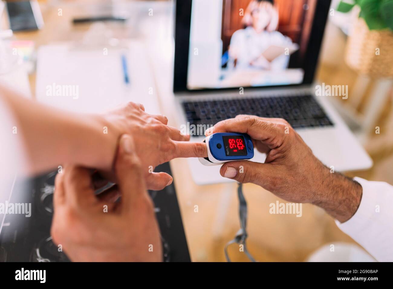 Male doctor examining patient through oximeter during telemedicine in ...