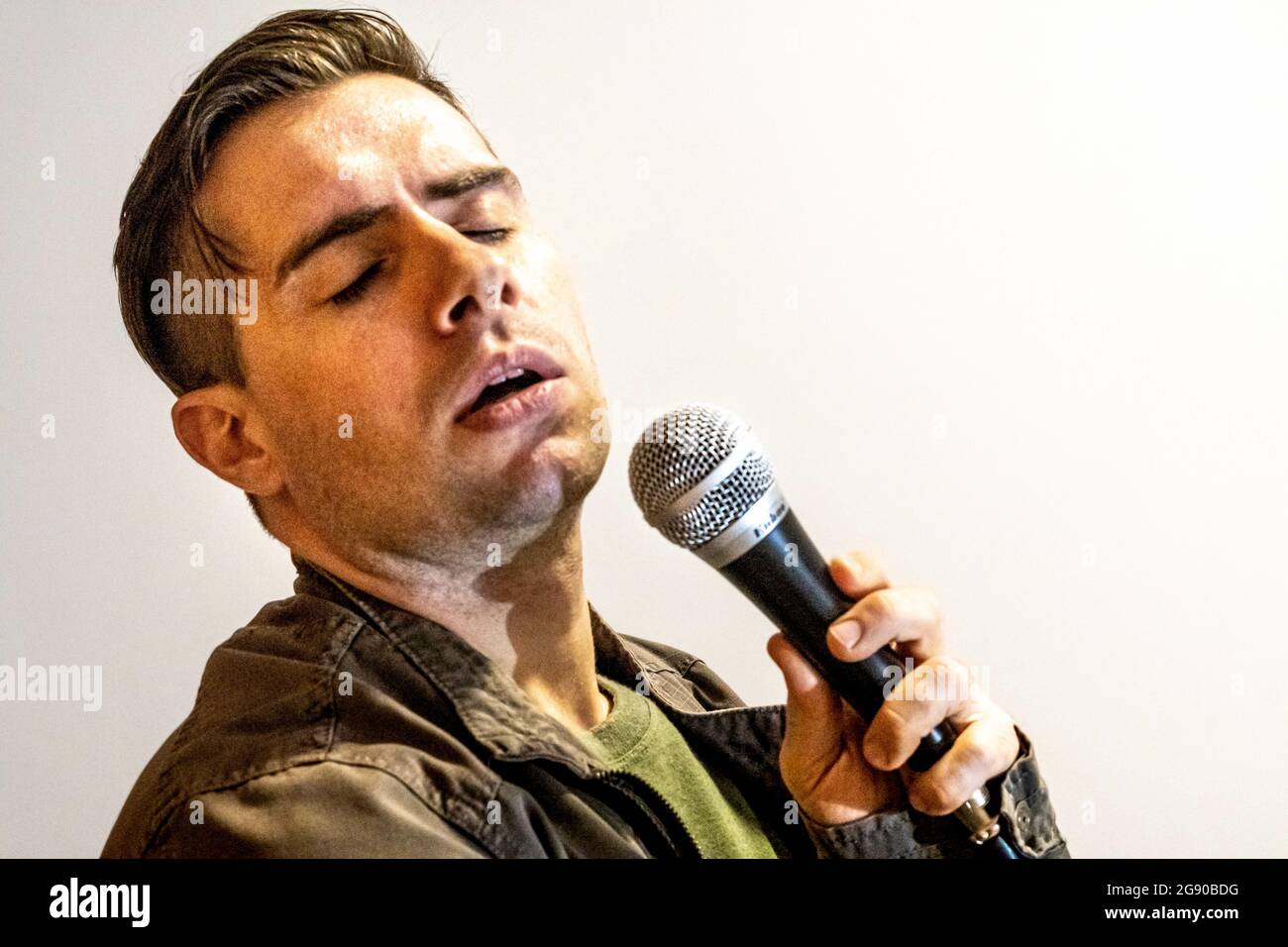 Man singing with a microphone on a white background Stock Photo - Alamy