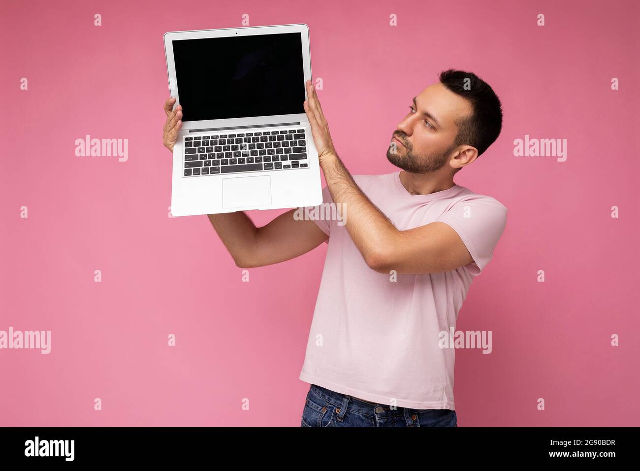 Handsome man holding laptop computer looking at laptop monitor in t ...