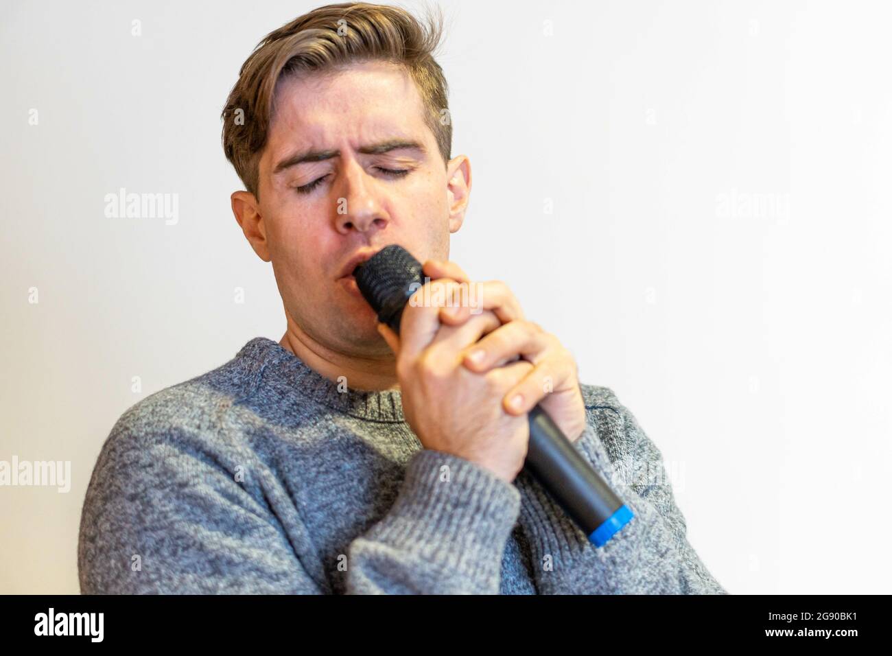 Man singing with a microphone on a white background Stock Photo - Alamy