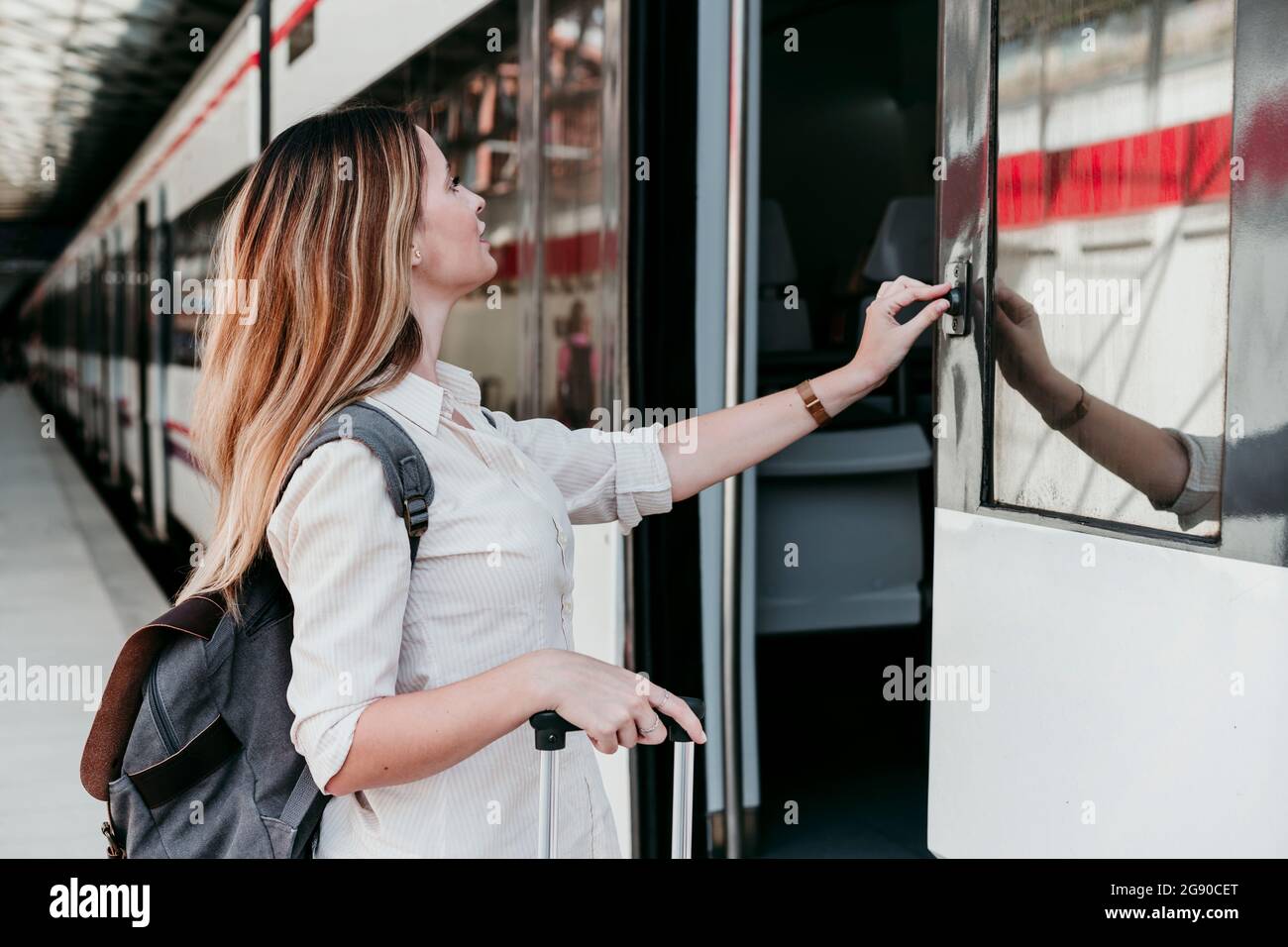 Young female passenger pressing button on train at railroad station ...