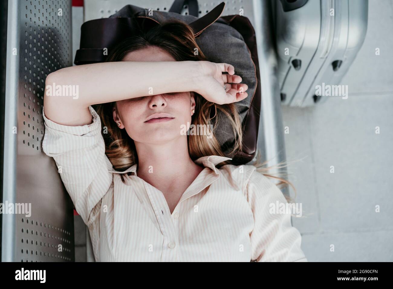 Young woman sleeping while lying on bench at railroad station Stock ...