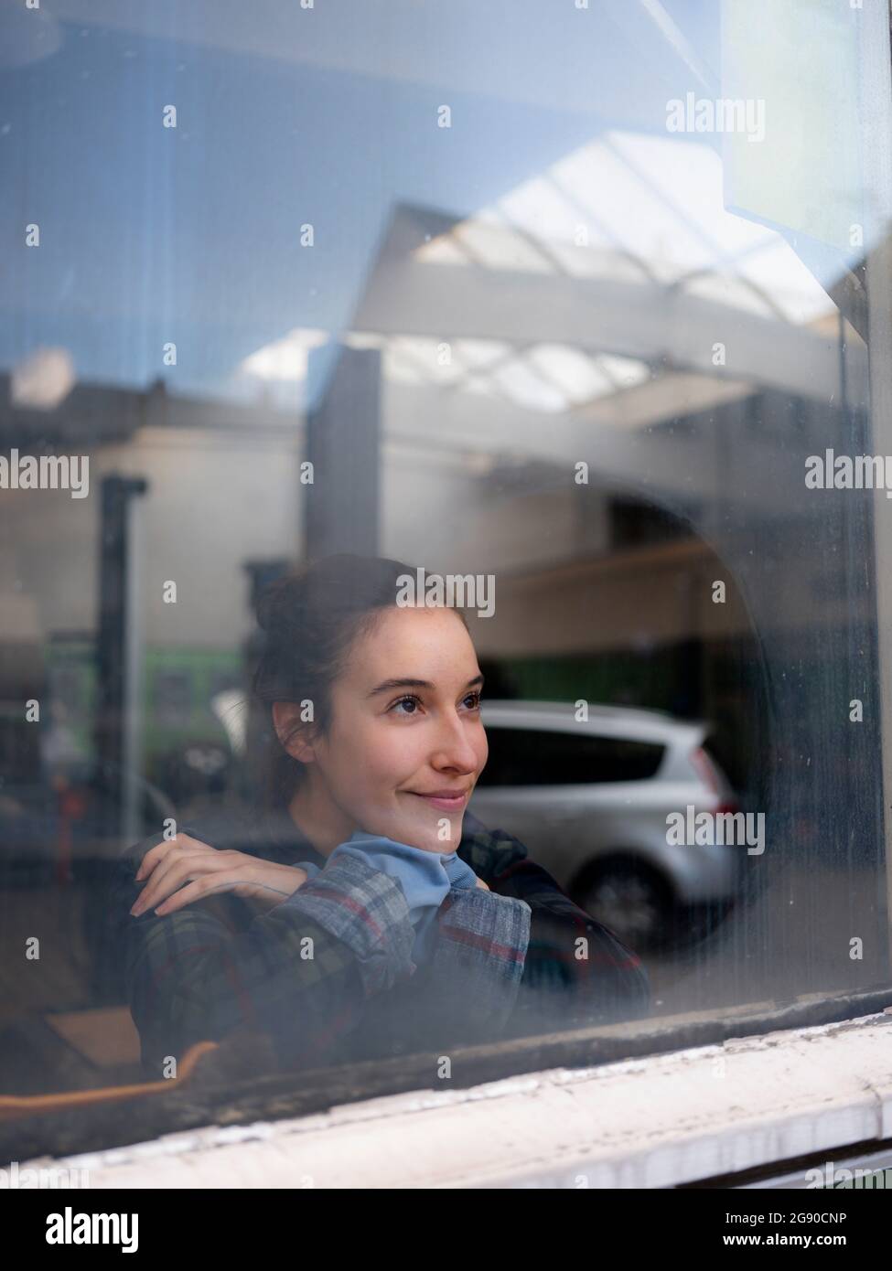 Female mechanic looking through window at workshop Stock Photo - Alamy