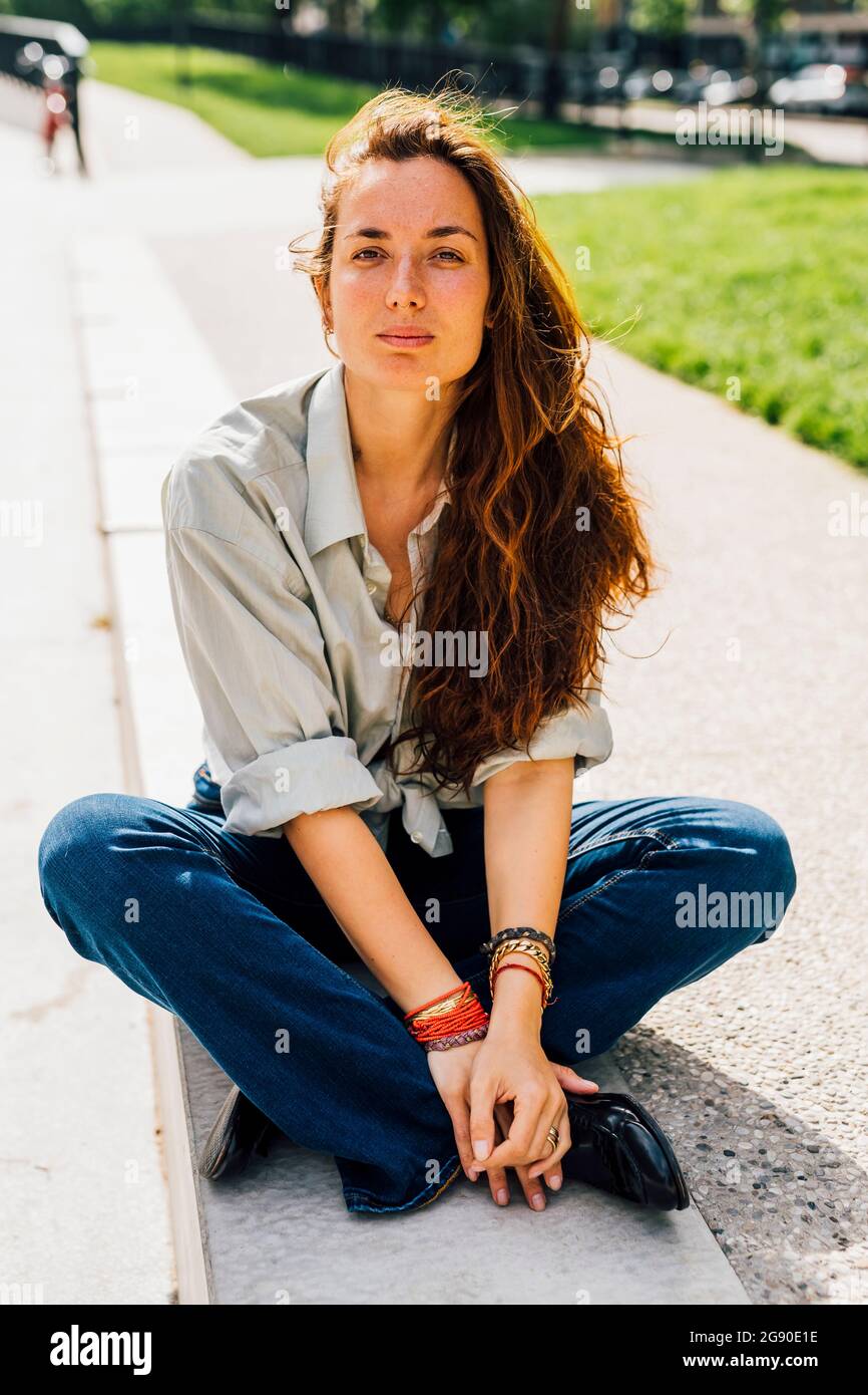 Beautiful woman sitting cross-legged on road Stock Photo - Alamy