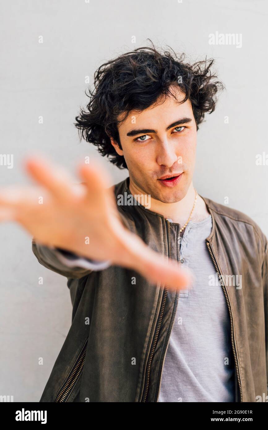 Man staring while stretching hand in front of wall Stock Photo - Alamy