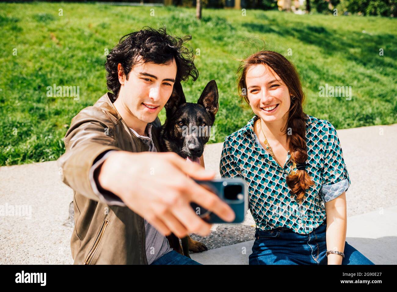 Smiling boyfriend taking selfie with dog and girlfriend through smart ...