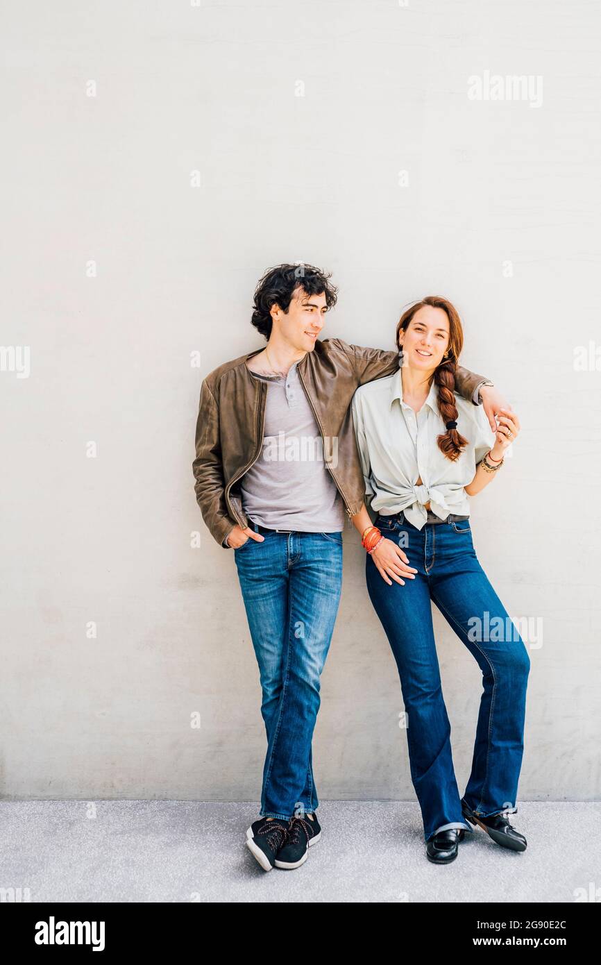 Smiling boyfriend looking at girlfriend while standing on footpath ...