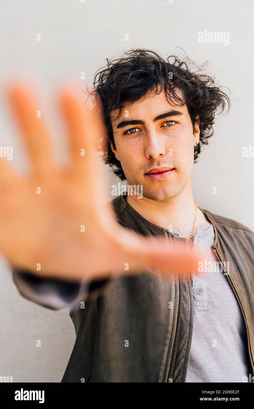 Young man stretching hand in front of wall Stock Photo - Alamy