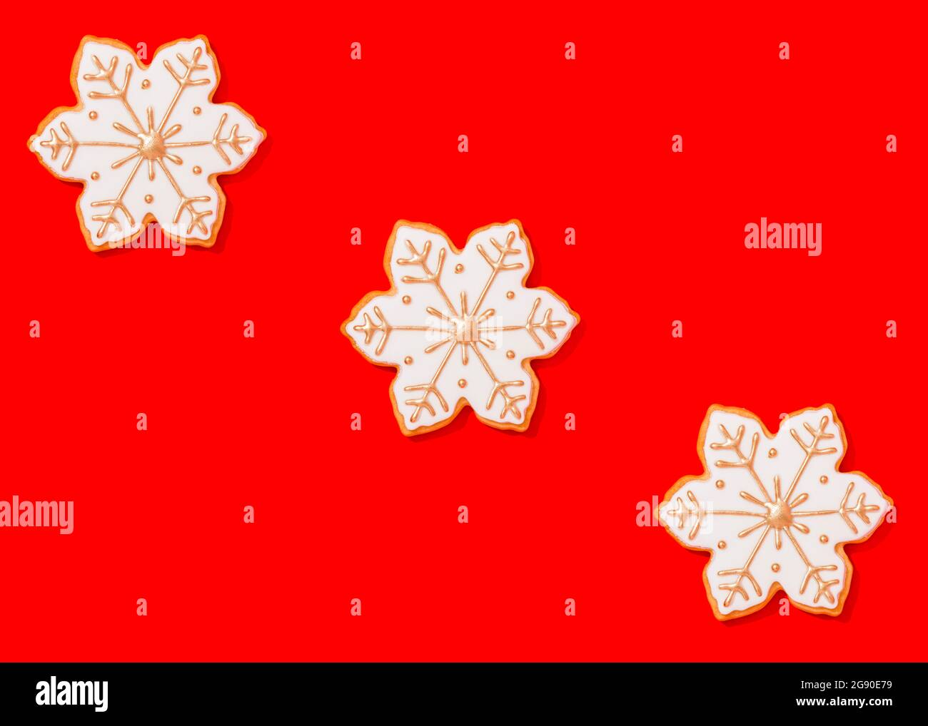 Three snowflake shaped Christmas cookies against vibrant red background ...
