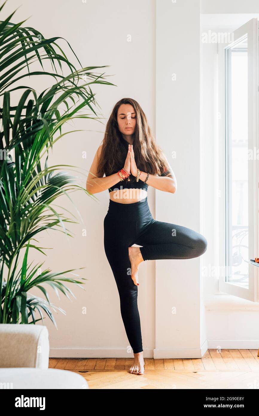 Woman practicing yoga while standing on one leg at home Stock Photo - Alamy