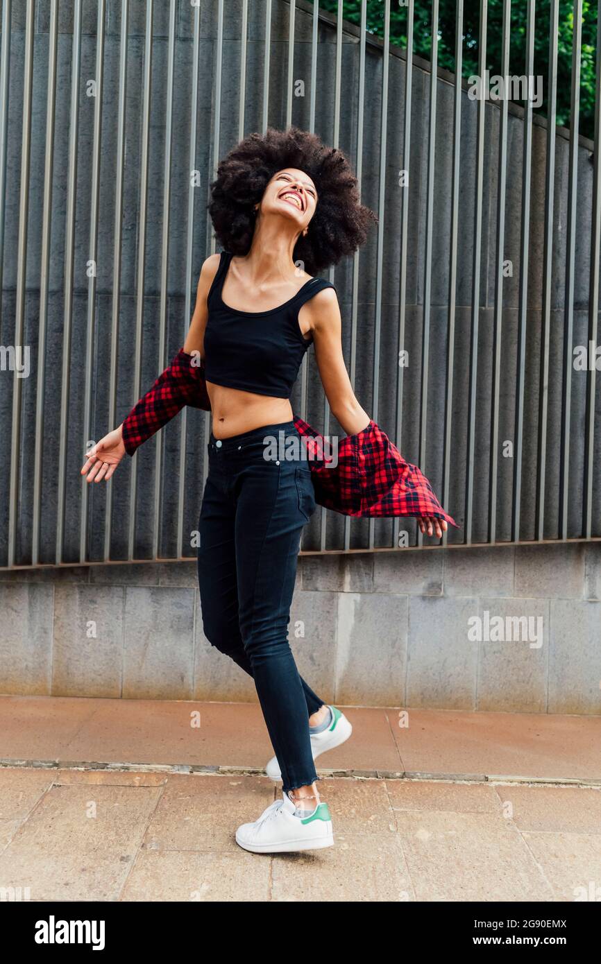 Happy young woman dancing in front of wall Stock Photo - Alamy