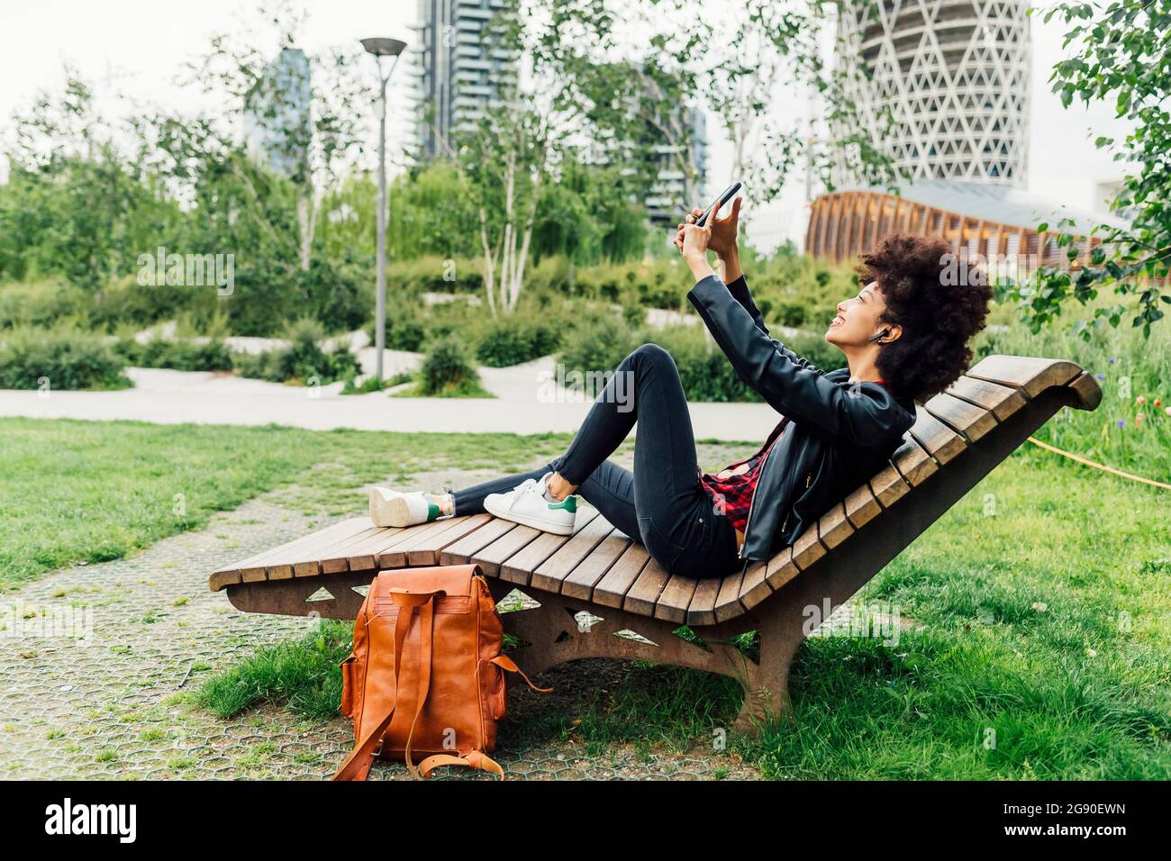 Woman taking selfie through smart phone while sitting on wooden chair ...