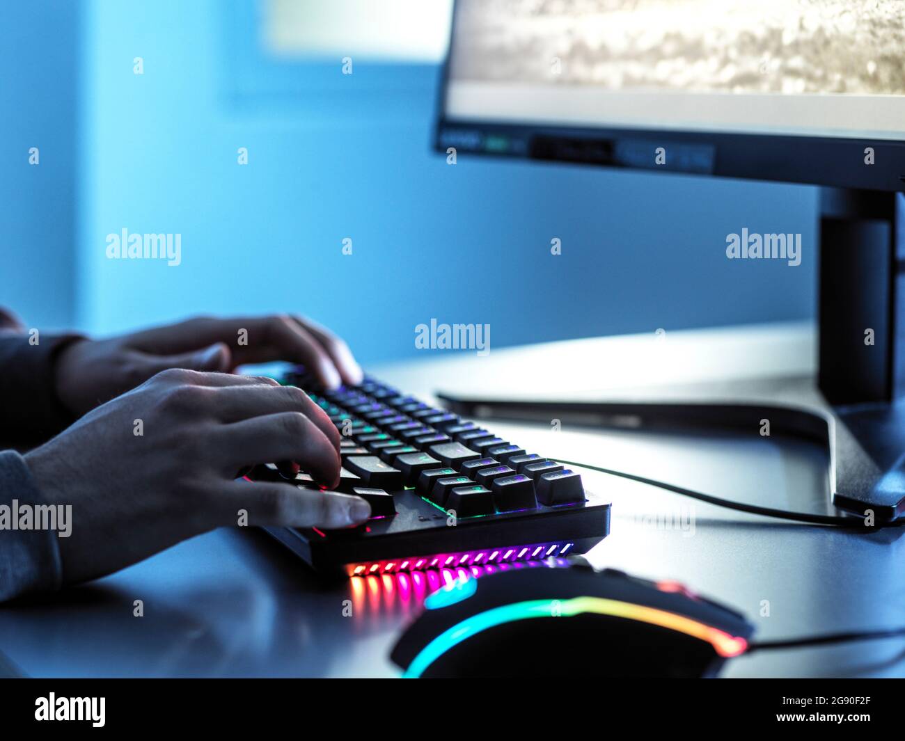 Teenage boy playing video game using keyboard on computer at table ...