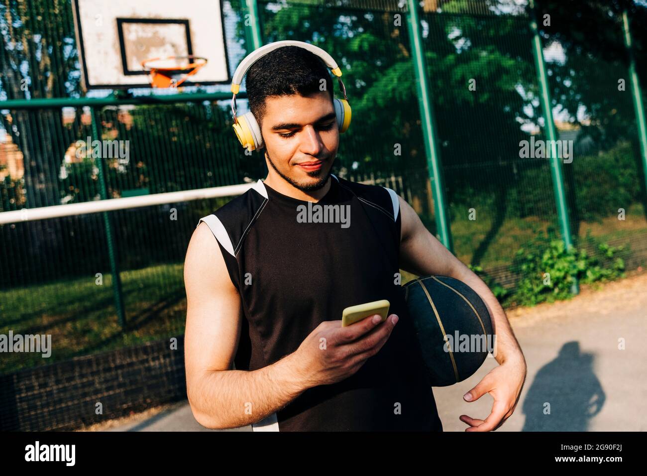 Basketball player listening music on headphones on court Stock Photo ...