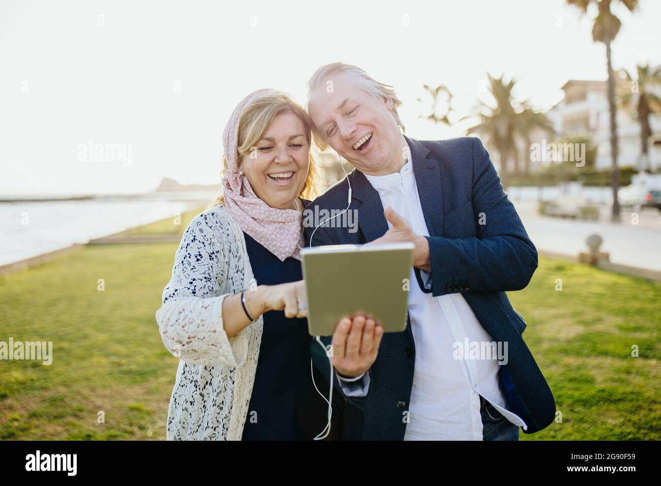 Mature Couple Laughing While Watching Video Through Digital Tablet