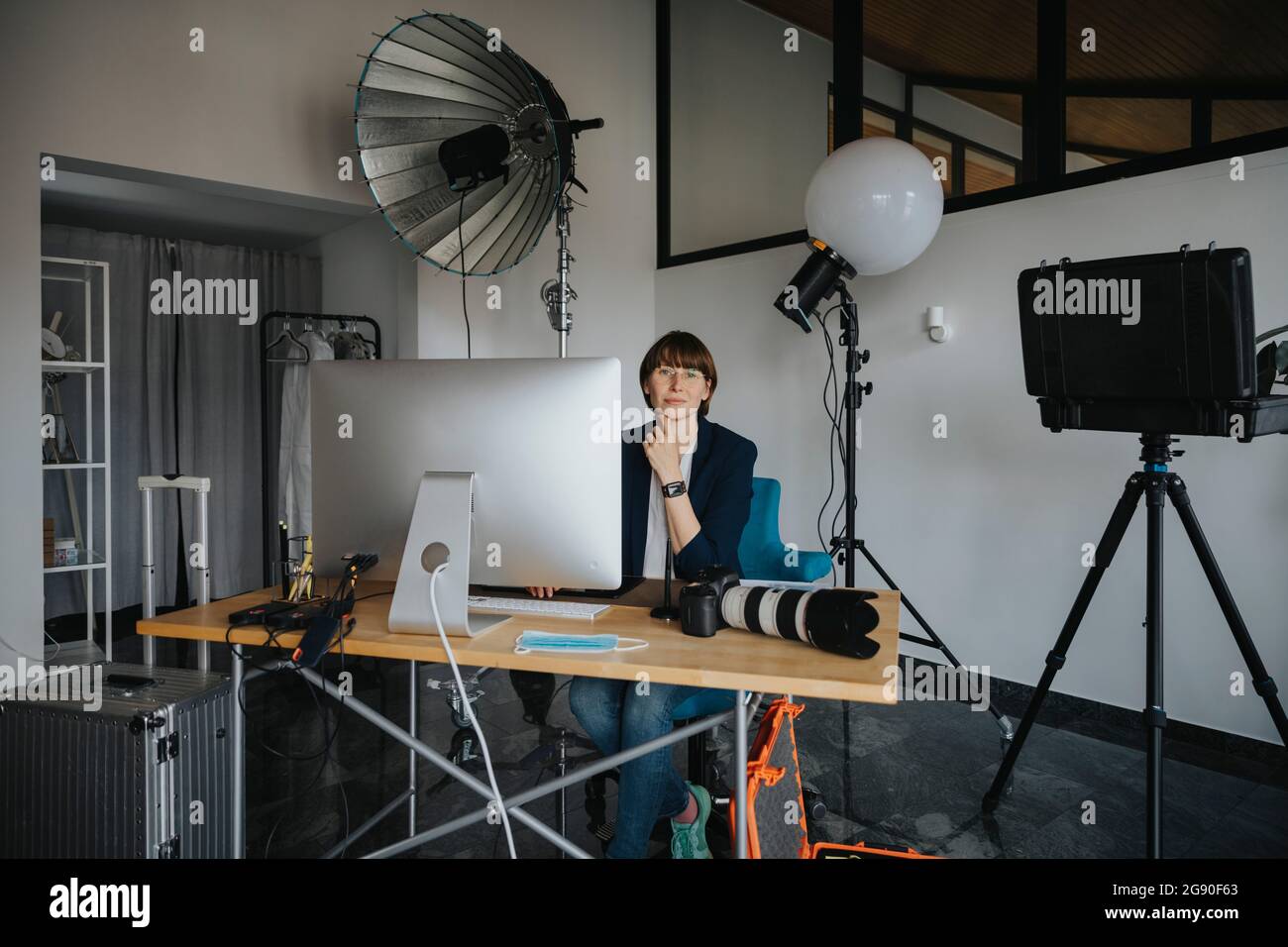 Female photographer sitting at desk in studio Stock Photo - Alamy