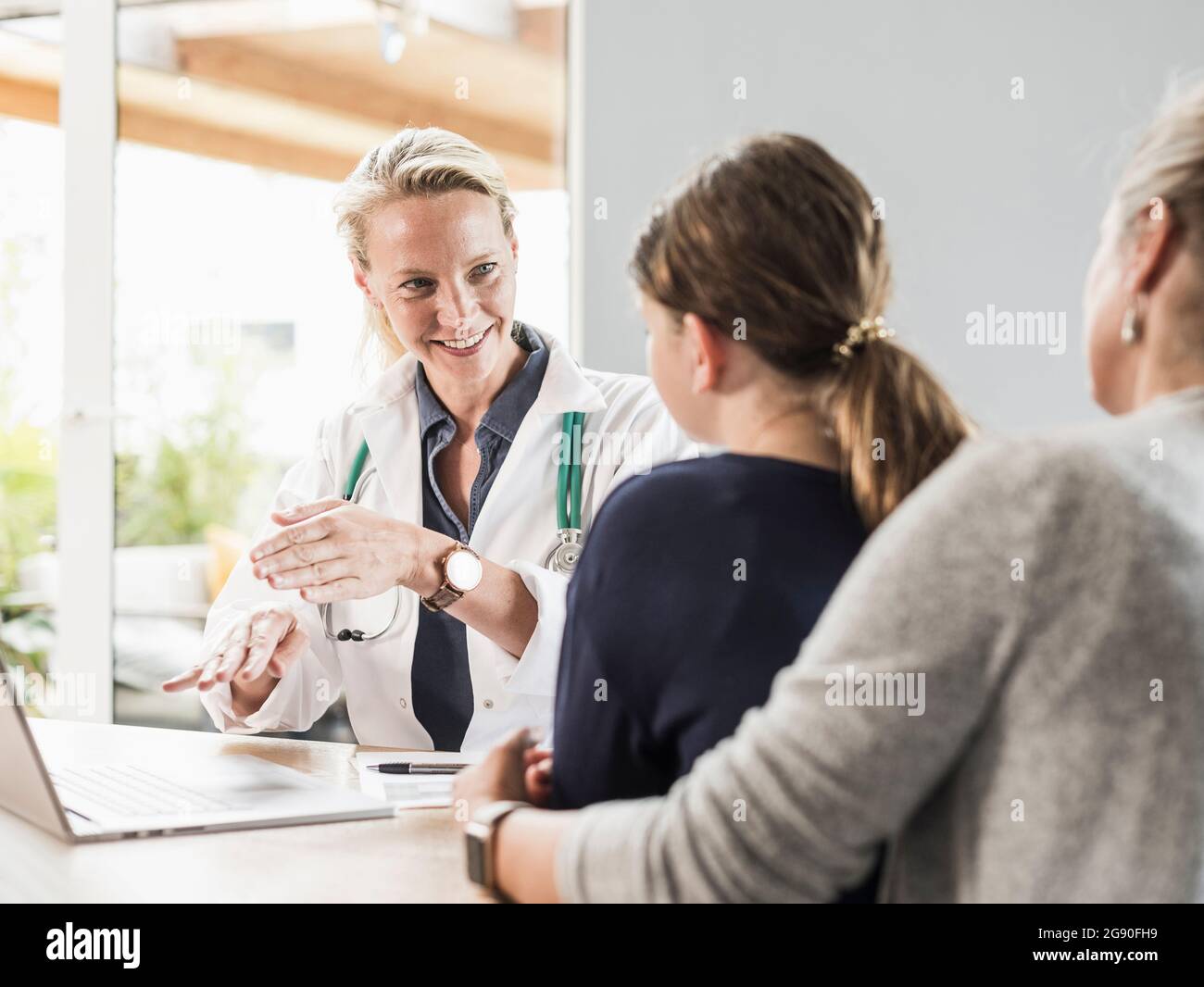 Smiling doctor giving advice to patient and woman at office Stock Photo ...