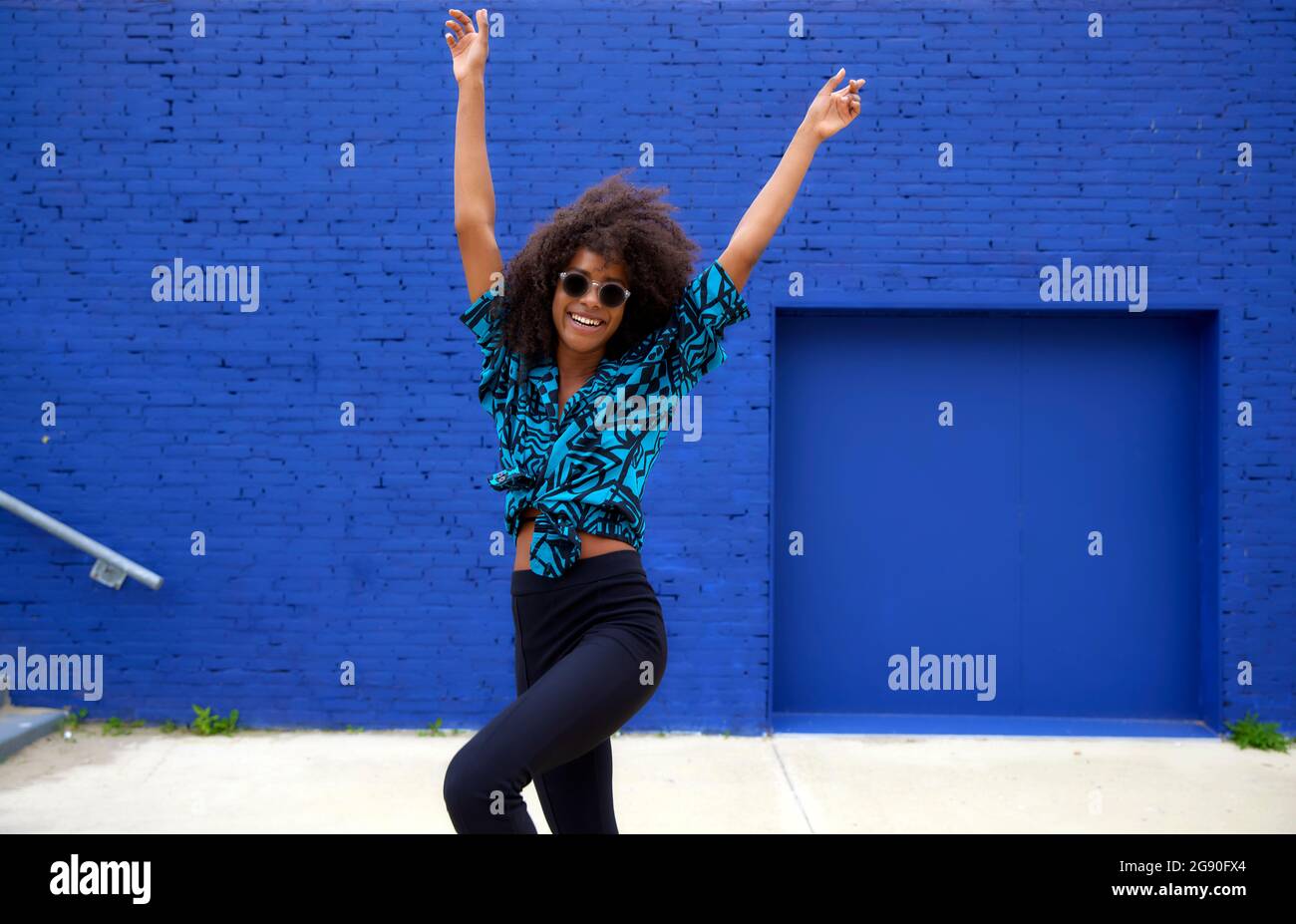 Carefree young Afro woman dancing with hands raised Stock Photo - Alamy