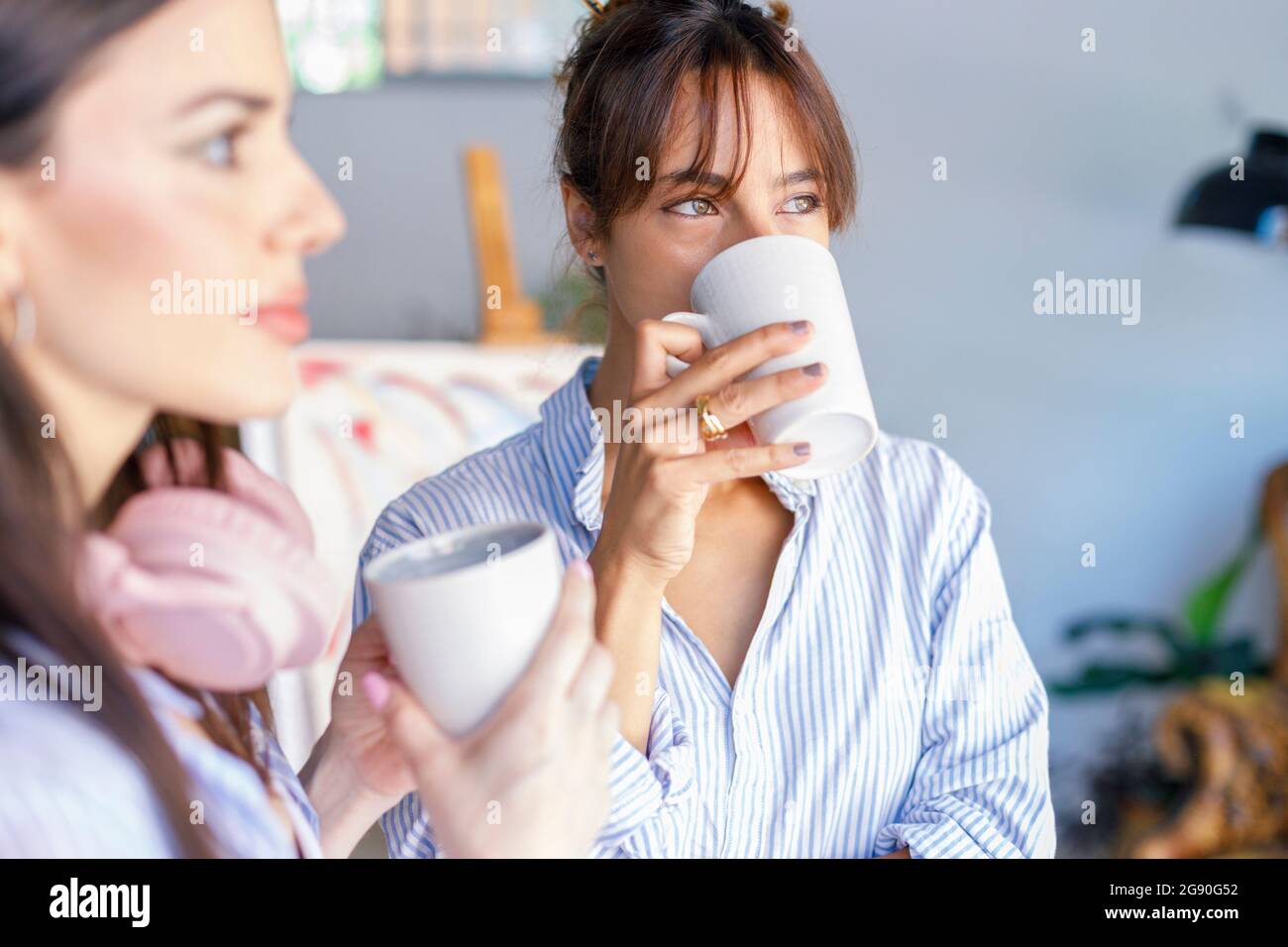 Female colleagues drinking coffee during break in studio Stock Photo ...