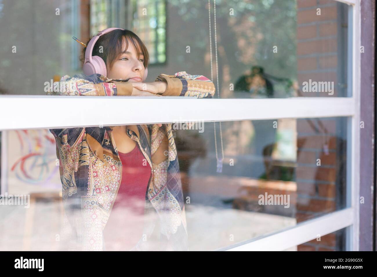 Female creative professional looking through studio window while ...