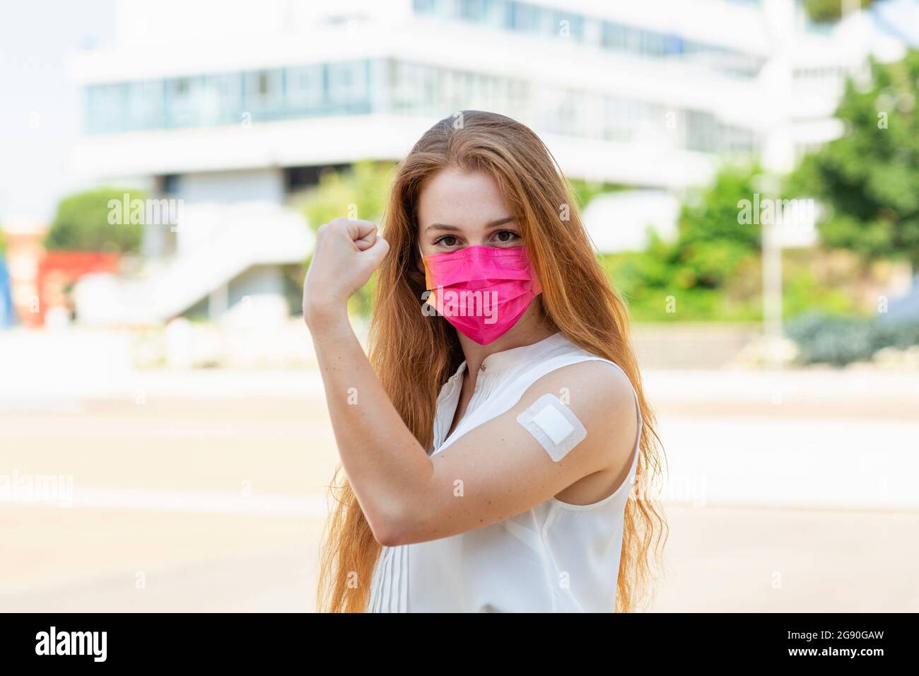 Female professional wearing protective face mask flexing muscles during ...