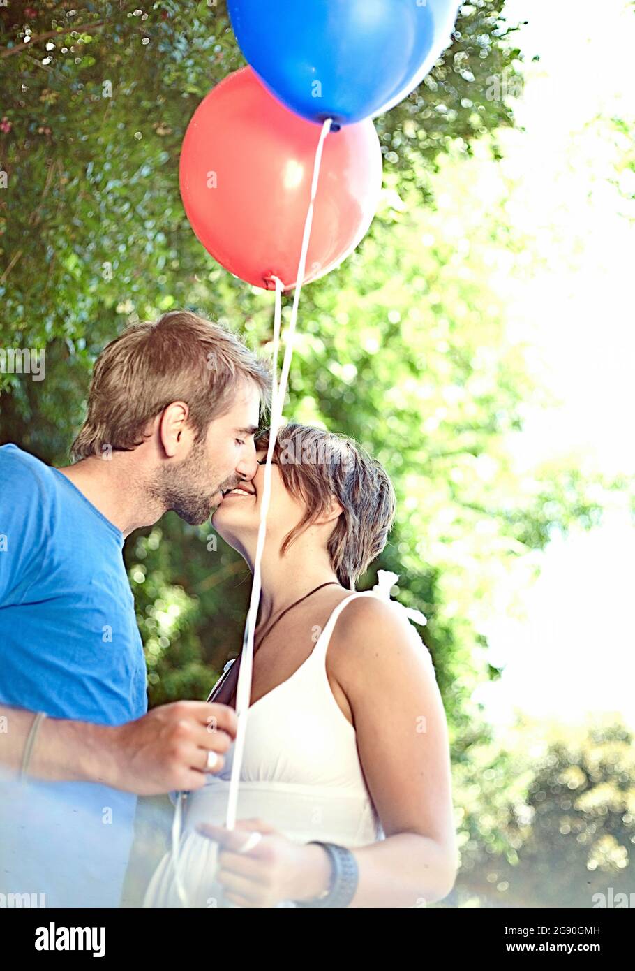 Young woman and man balloons kissing at park Stock Photo - Alamy