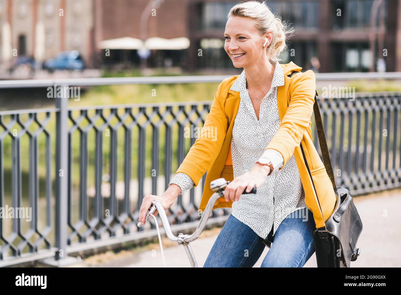 Smiling female commuter with shoulder bag riding bicycle Stock Photo ...