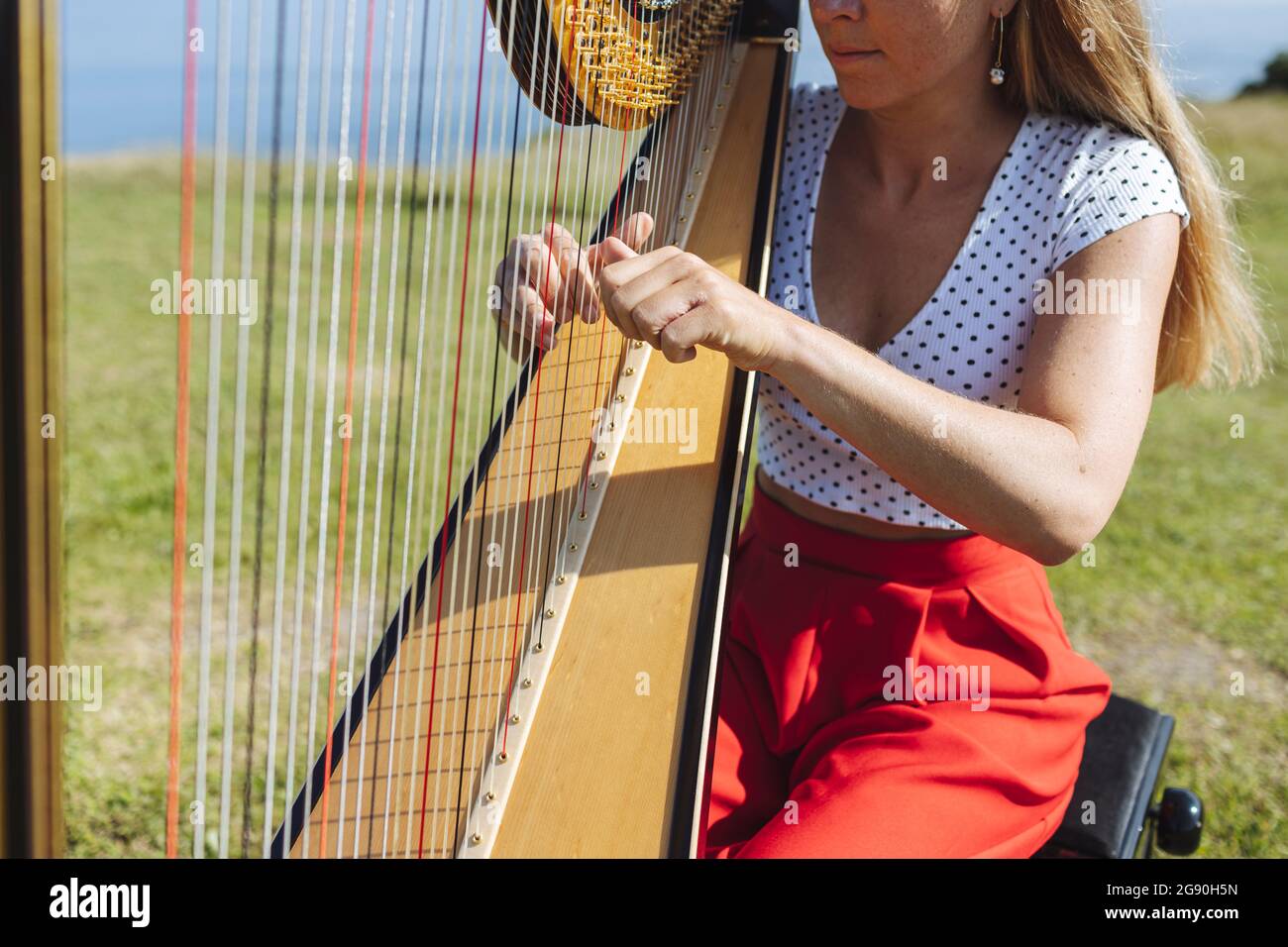 Female musician playing harp on sunny day Stock Photo - Alamy