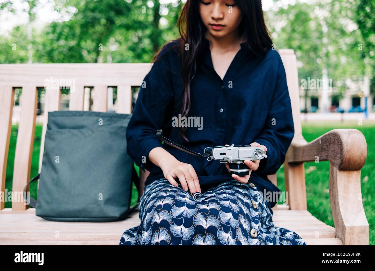 Female photographer holding camera while sitting on bench Stock Photo ...
