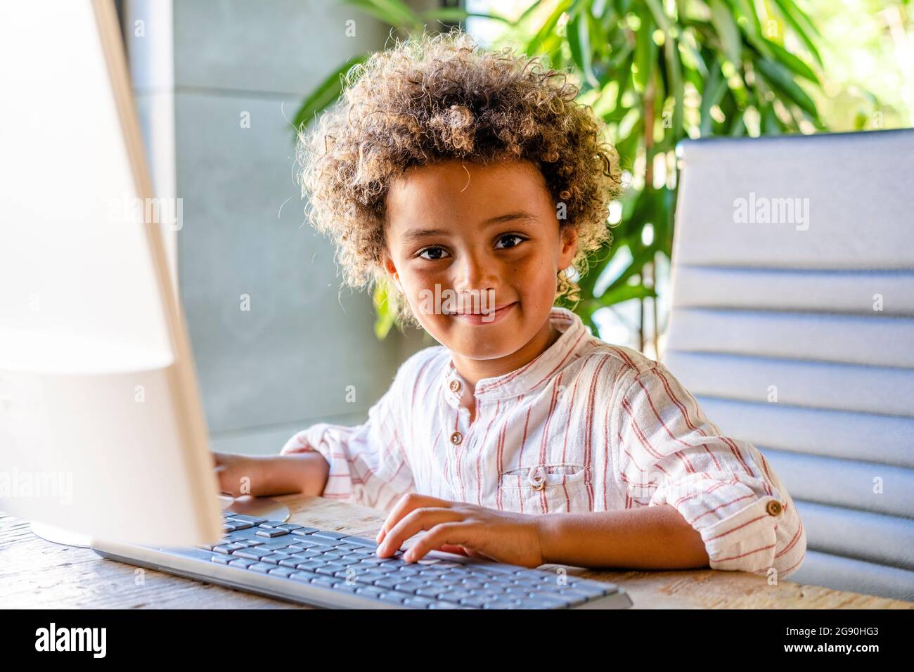 Smiling cute boy with computer at home Stock Photo - Alamy