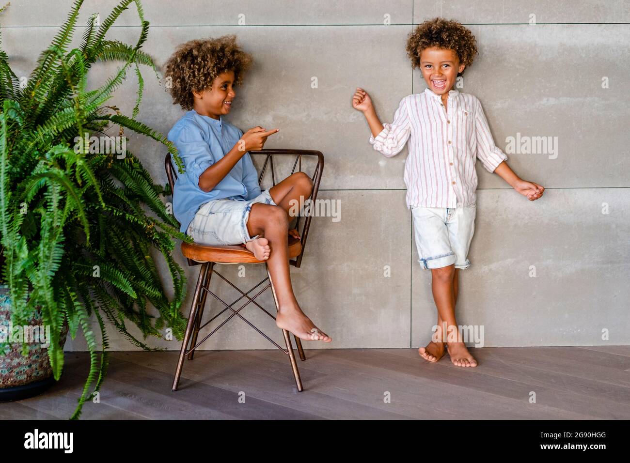 Boy gesturing at brother standing in front of wall at home Stock Photo ...