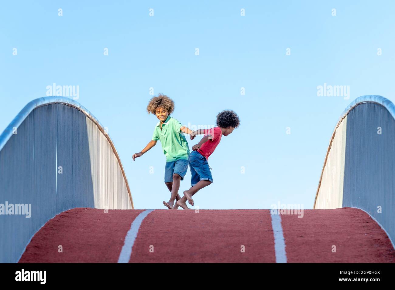 Boys playing on bridge in front of sky Stock Photo - Alamy