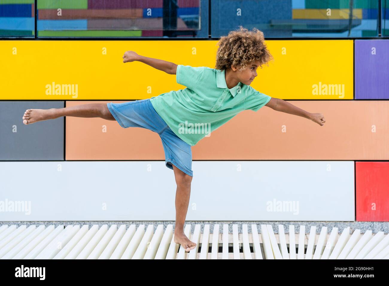 Boy with arms outstretched balancing on bench Stock Photo - Alamy