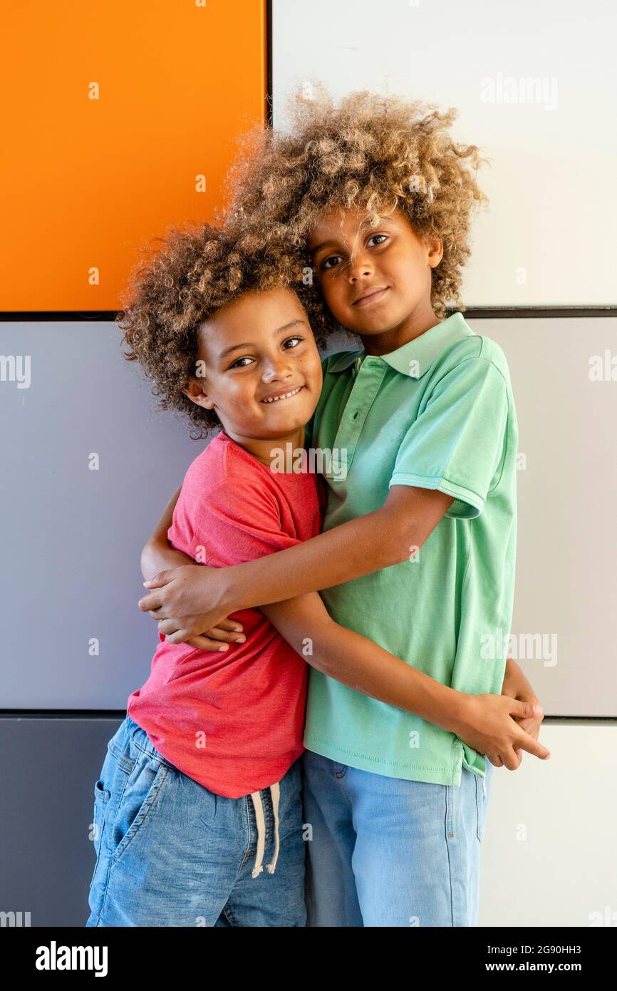 Brothers embracing in front of colorful wall Stock Photo - Alamy
