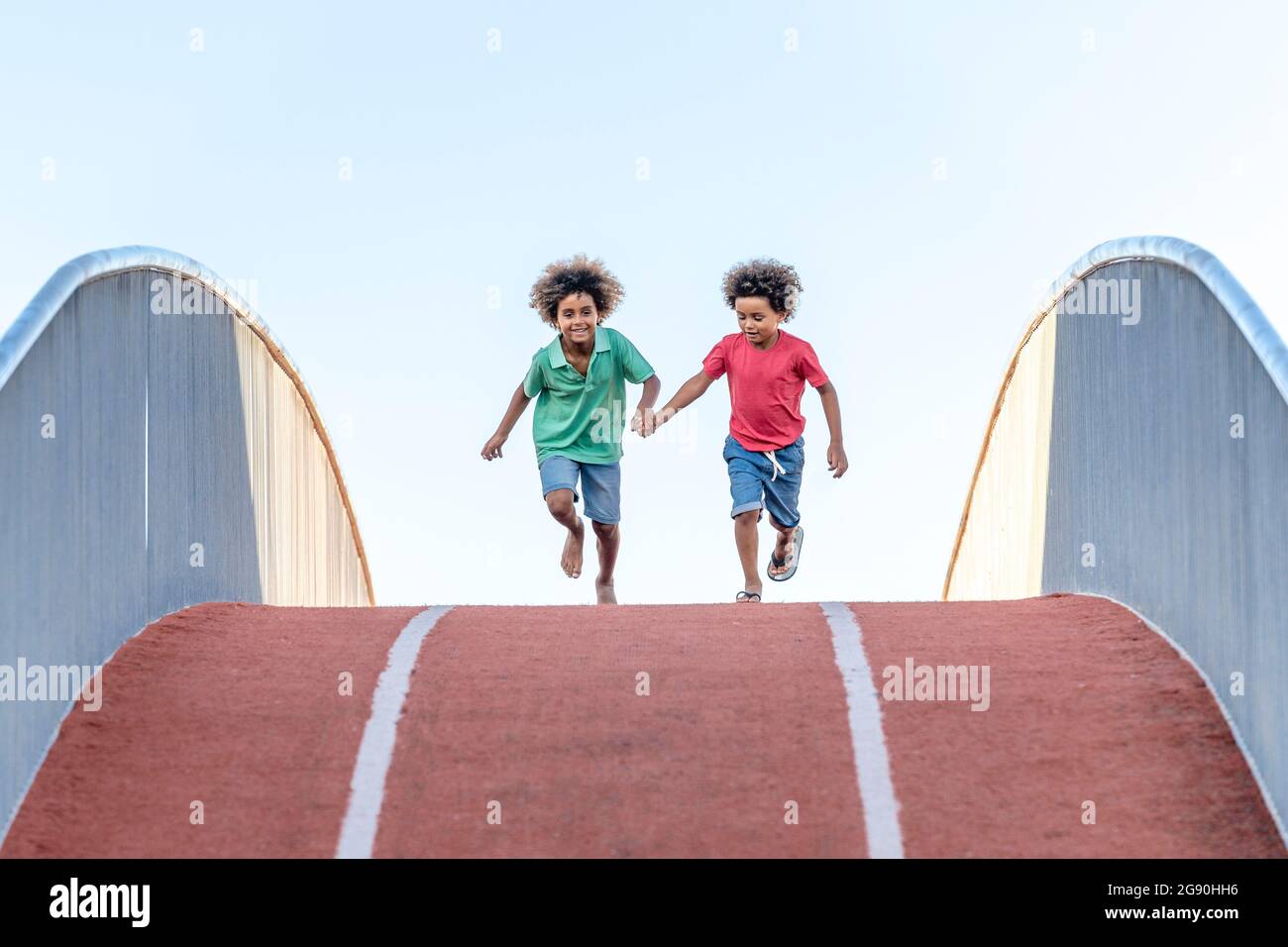 Boys with holding hands running on footbridge Stock Photo - Alamy