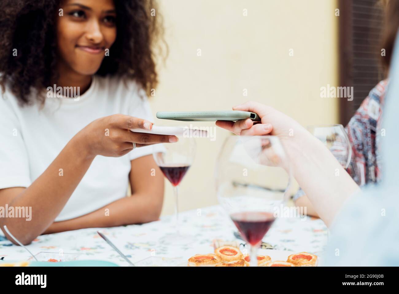 Friends sharing mobile phone while sitting by table Stock Photo - Alamy