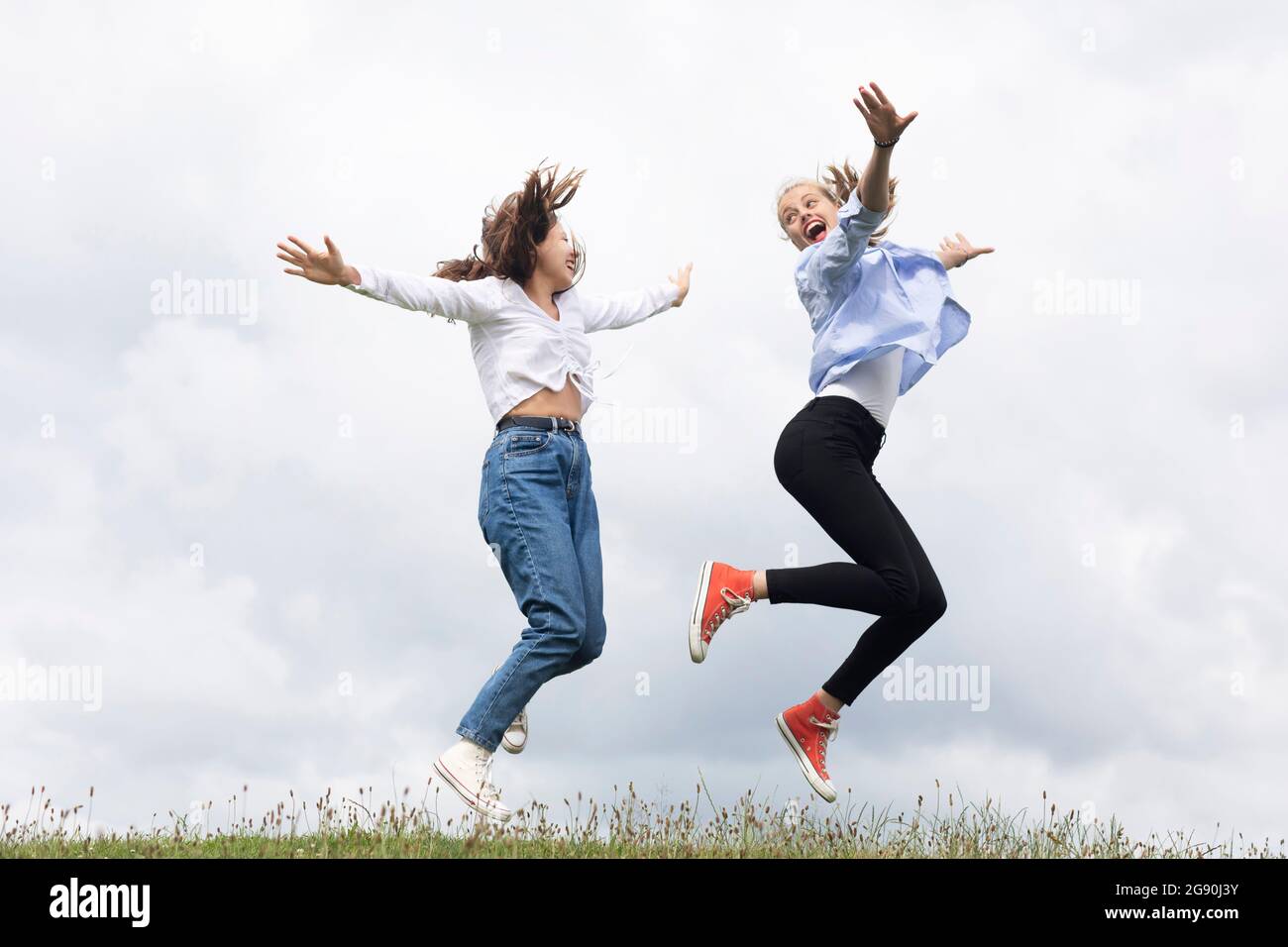 Carefree young female friends jumping on grass Stock Photo - Alamy